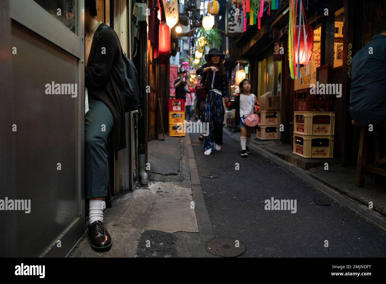With half of her body out in the alleyway, a woman eats dinner in a ...