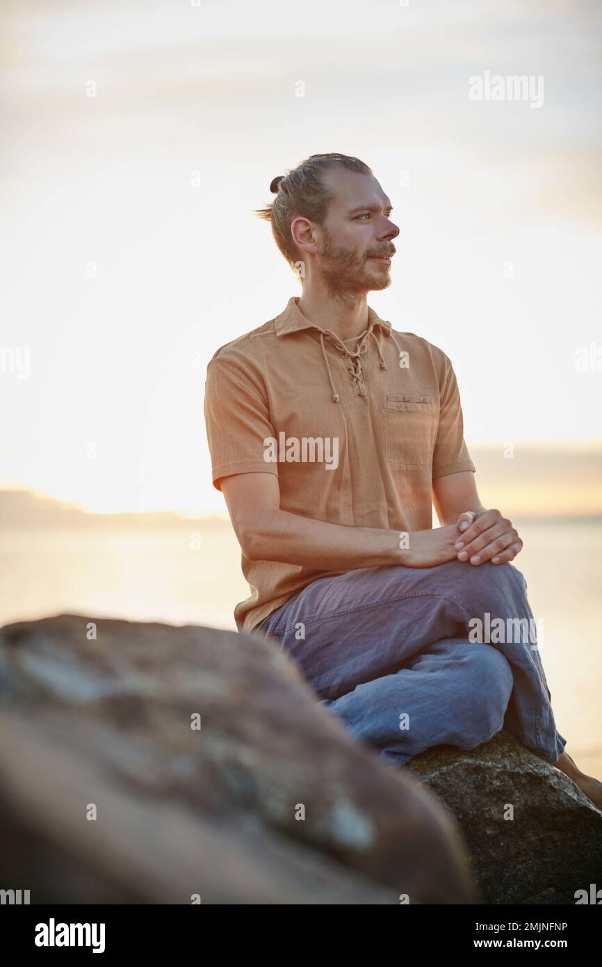 See the beauty in every moment. a peaceful man sitting on a rock at the ...