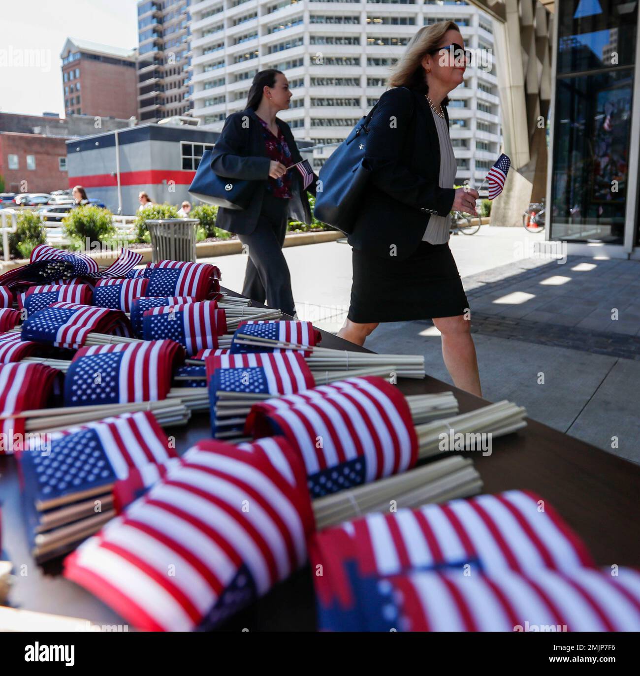 Arriving visitors walk past stacks of American flags that were being ...