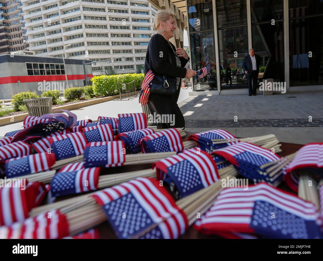Arriving visitors walk past stacks of American flags that were being ...