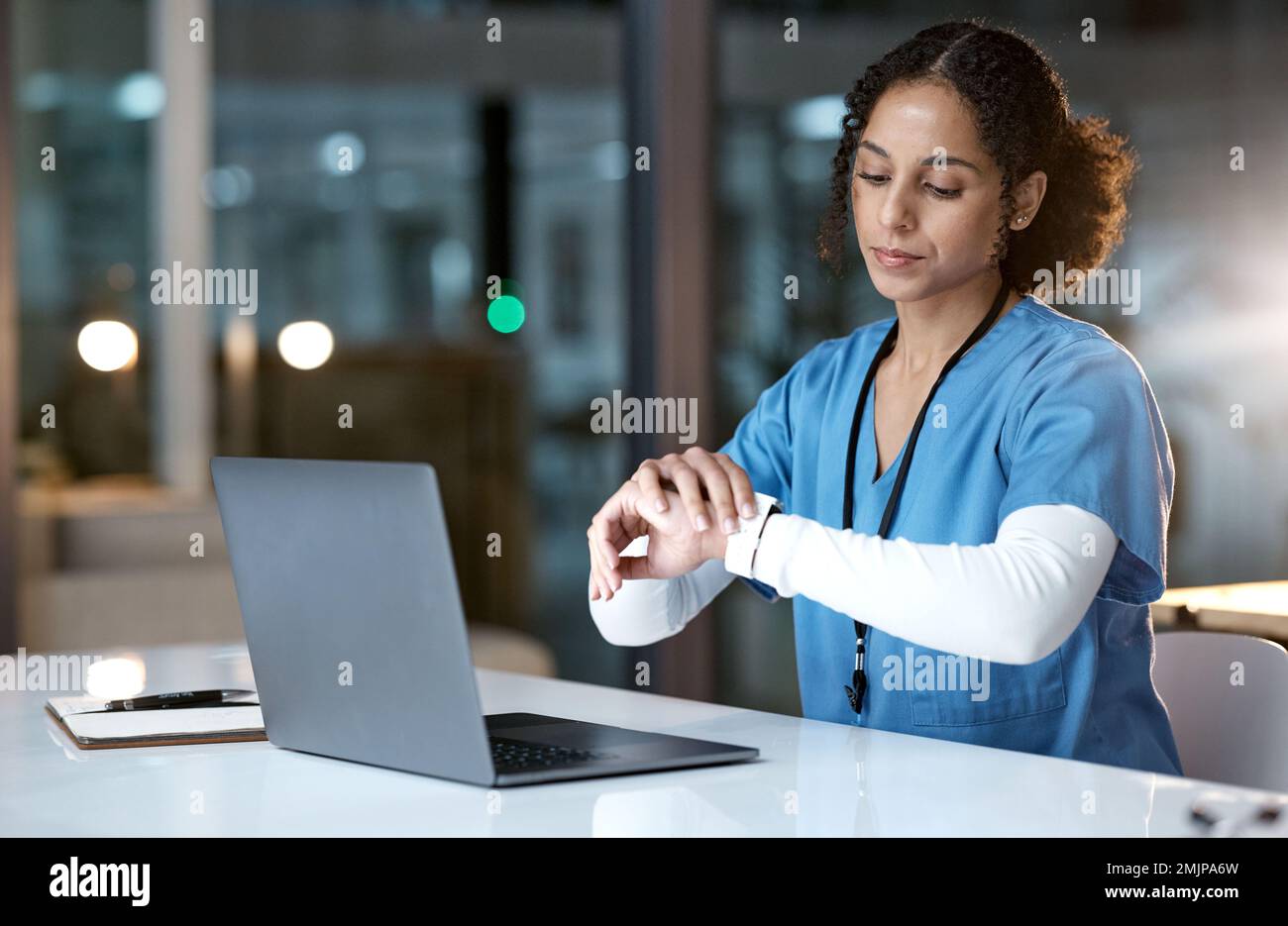 Laptop, watch and night with a black woman nurse working overtime on ...