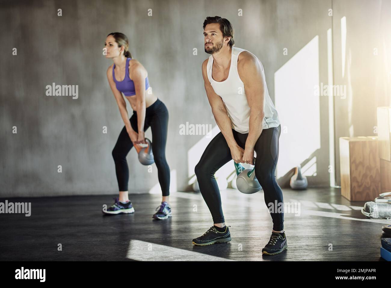 Its about strength. two young people working out in the gym using ...