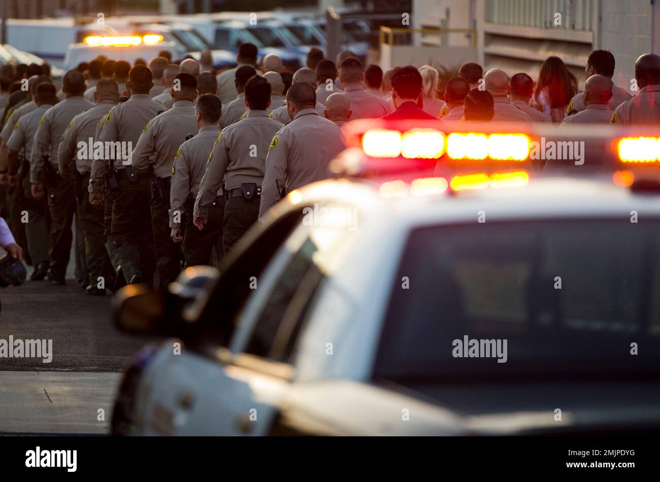 Los Angeles County Sheriff's deputies walk in a procession behind a ...