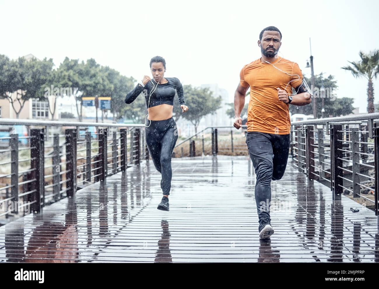 Personal trainer, rain and athletes running as exercise on a city ...