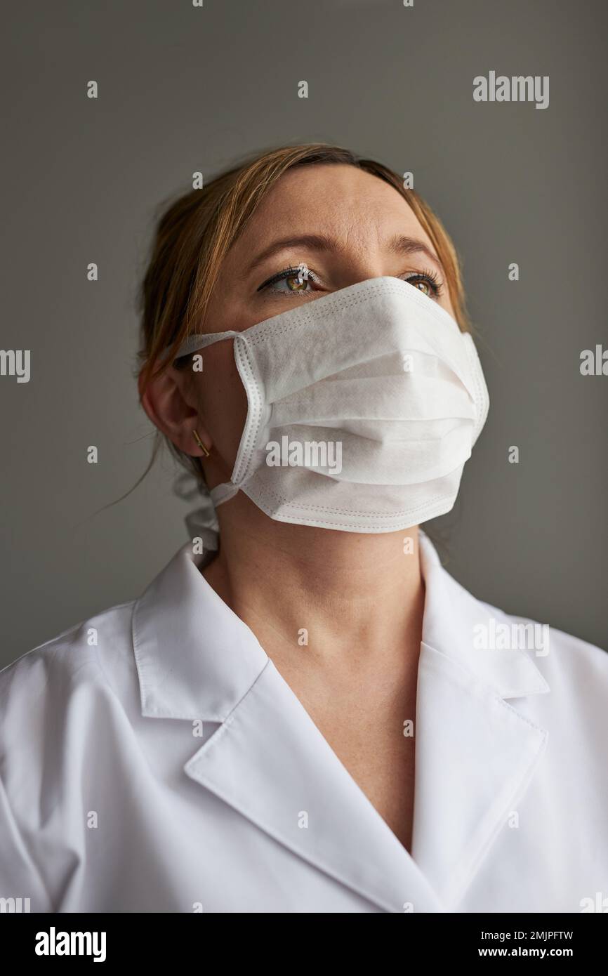 Doctor with face covered with mask. Portrait of young woman wearing the ...