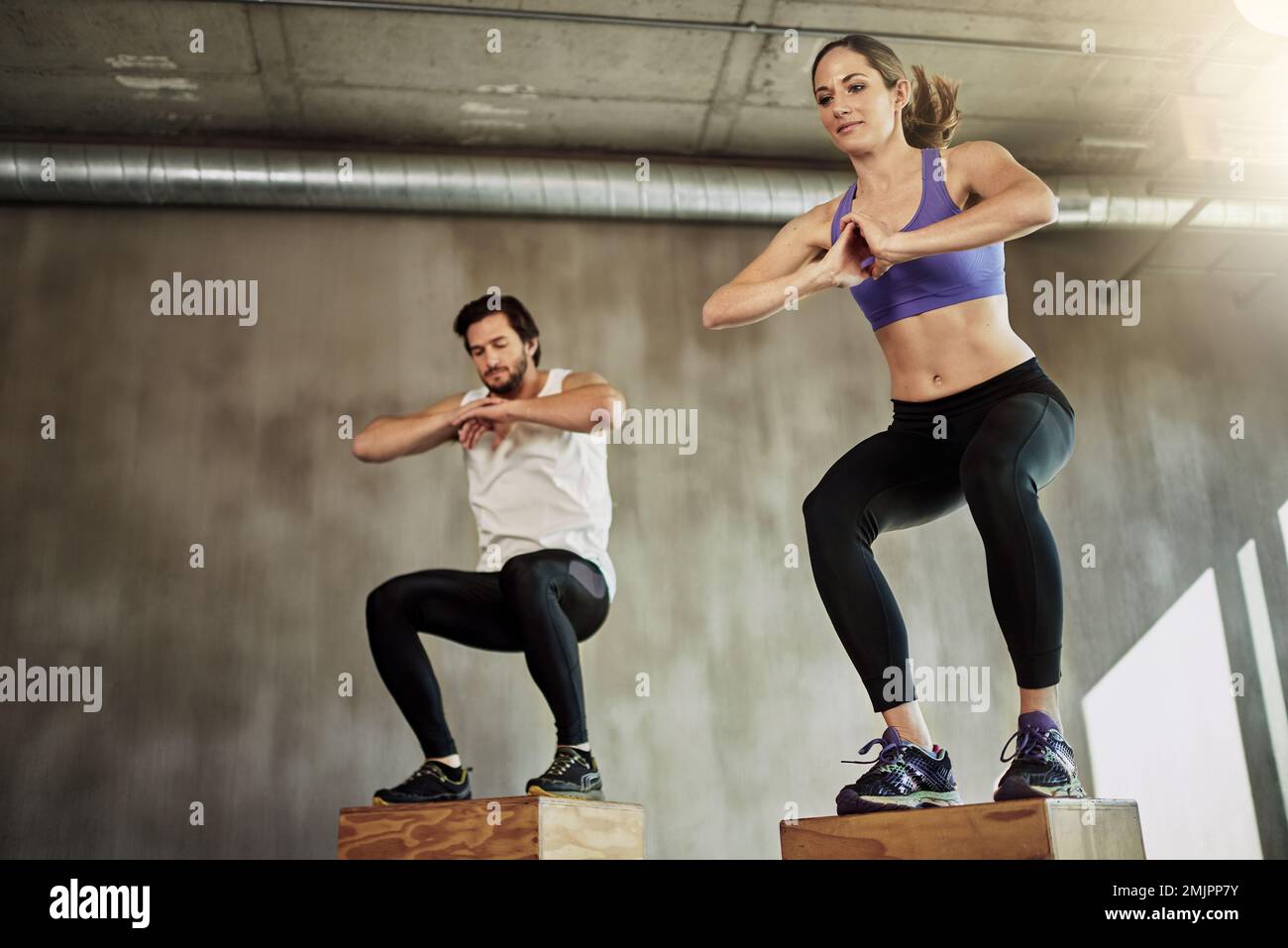 Every workout counts. two young people box jumping as part of their ...