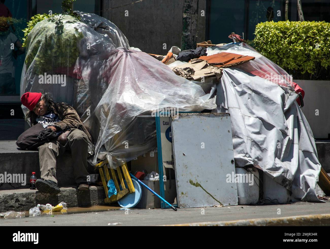 A homeless man sleeps next to his improvised shelter on a sidewalk in ...