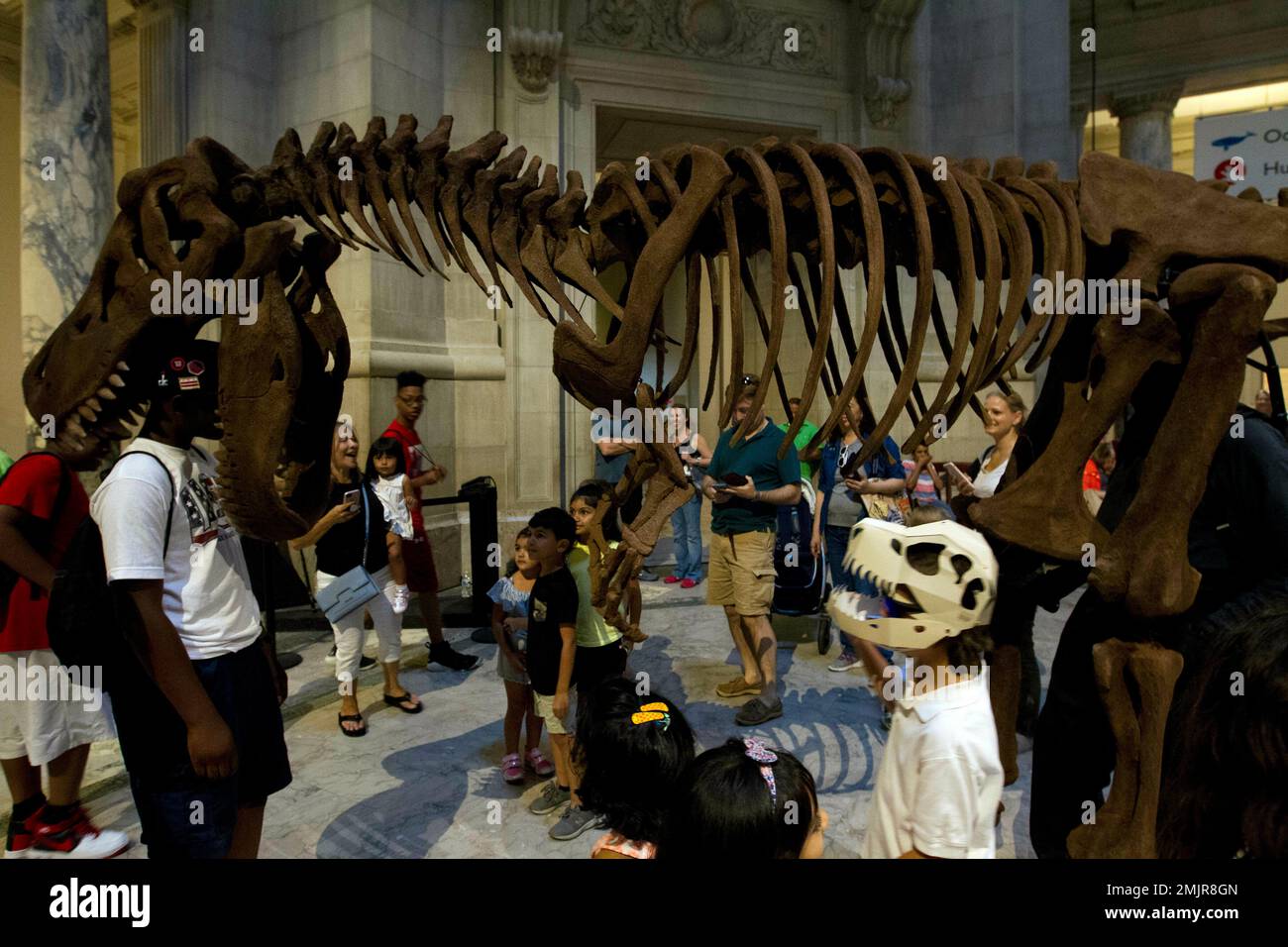 Visitors play with a model of a Tyrannosaurus rex during the ...