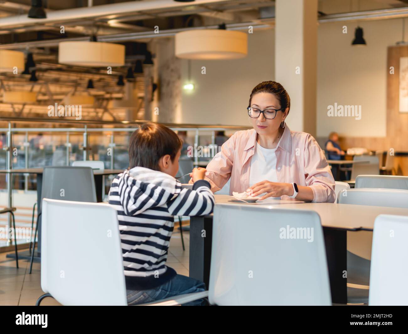 Mother and son are eating in cafe. Family on food court in shopping ...