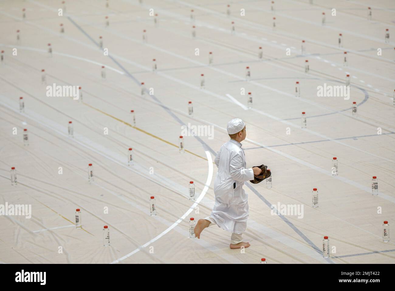 A boy runs between water bottles placed on the floor of a sports venue ...