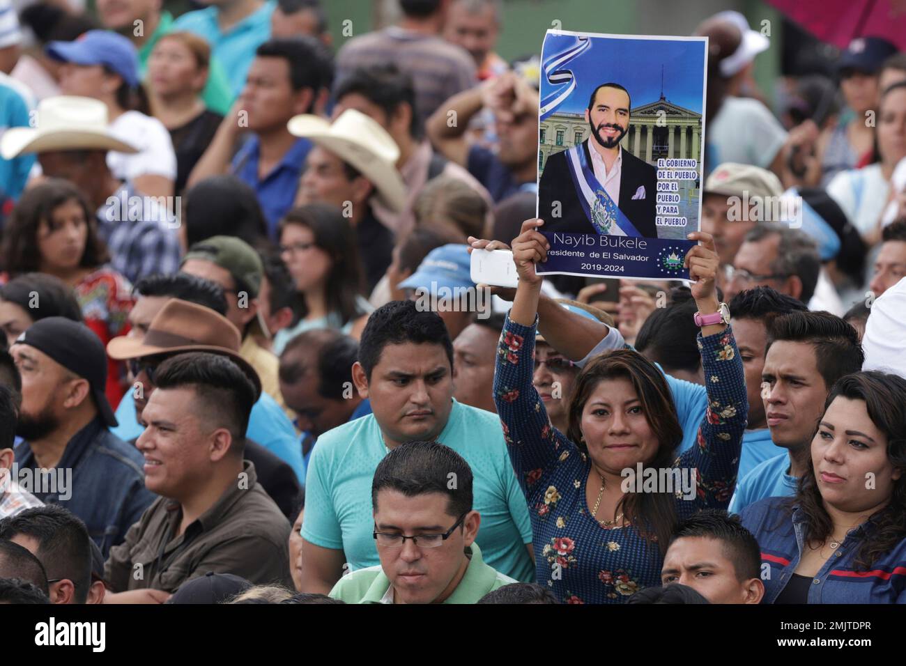 A woman holds up a poster that shows and image of El Salvador's newly ...