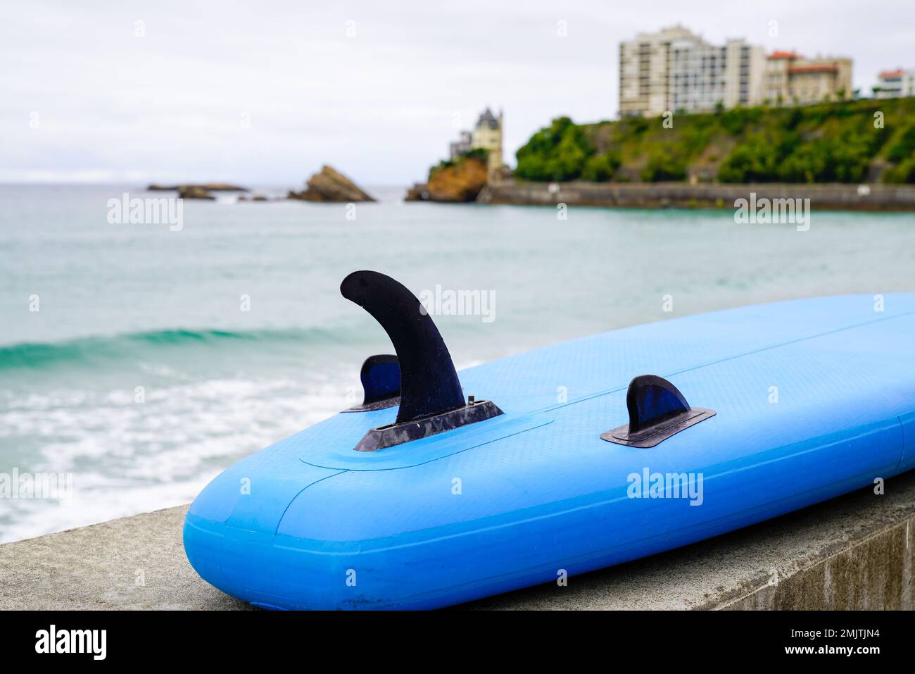 blue surfboard laid on waterfront sea beach facing the Atlantic ocean ...