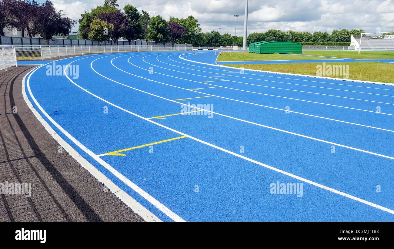 Athletics running blue track in a sports stadium Stock Photo - Alamy