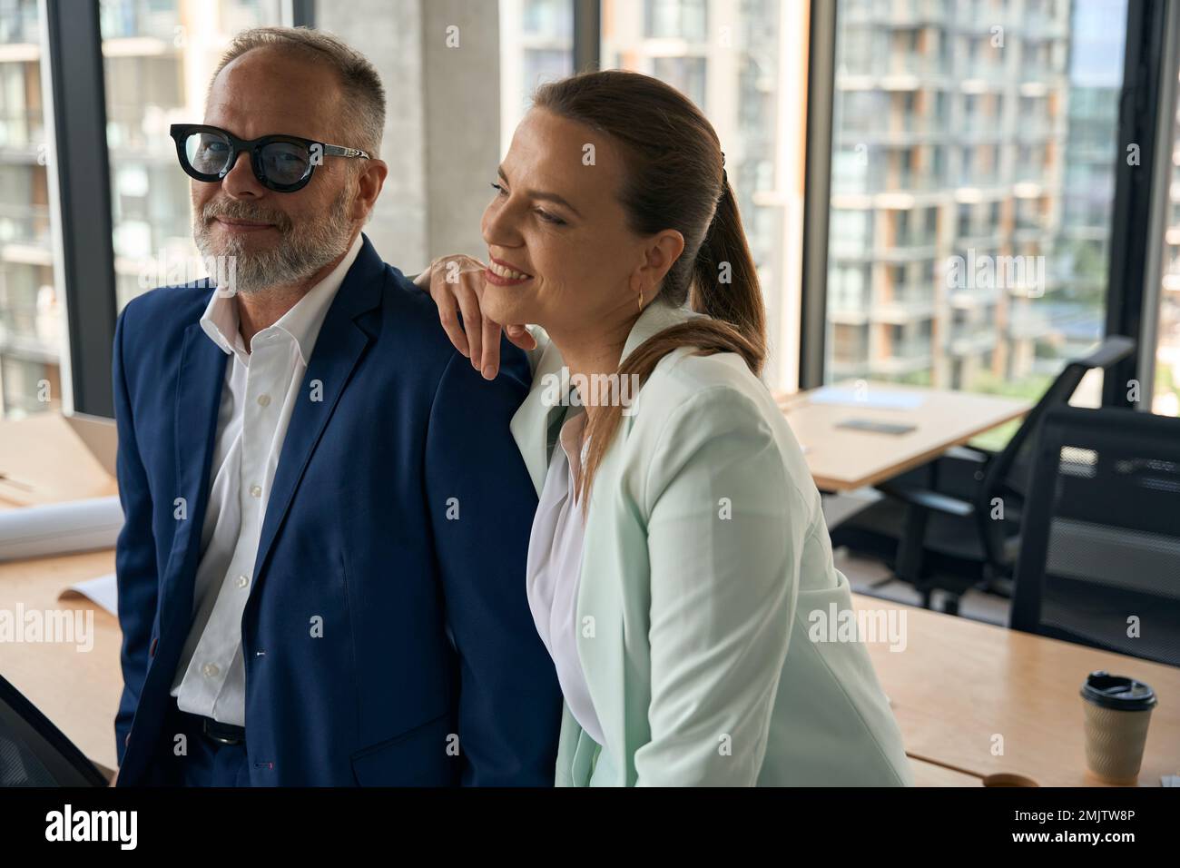 Mirthful woman and man in business suits posing at workplace Stock ...