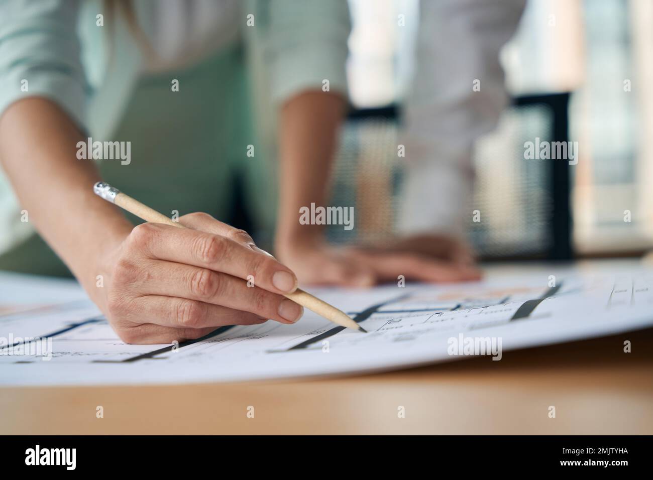 Busy female office worker implementing changes into plan with pencil ...