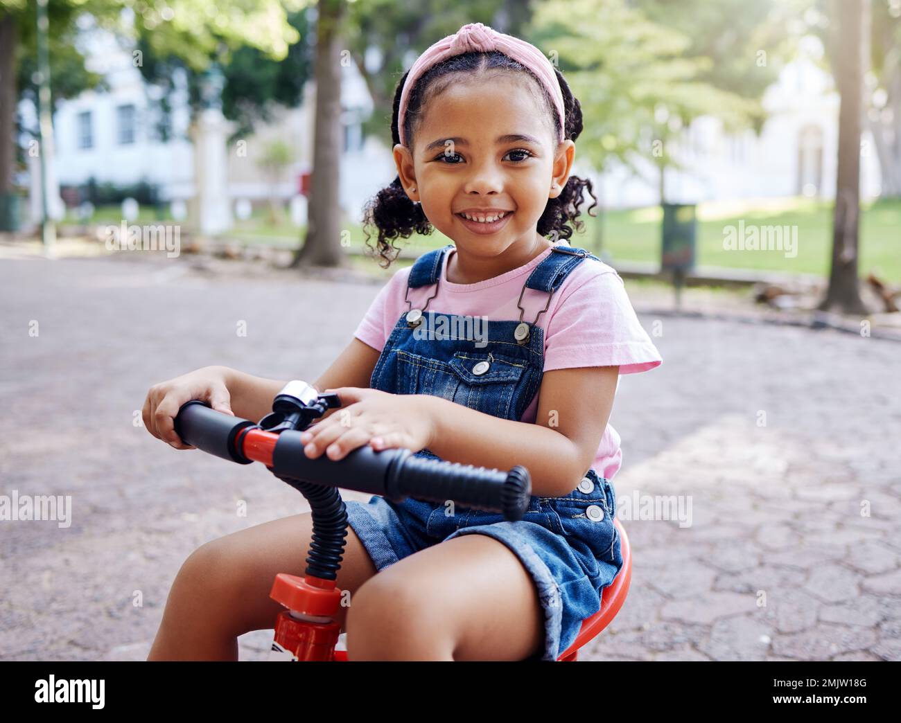 Portrait, young girl on bike in park and happy child outdoor with ...
