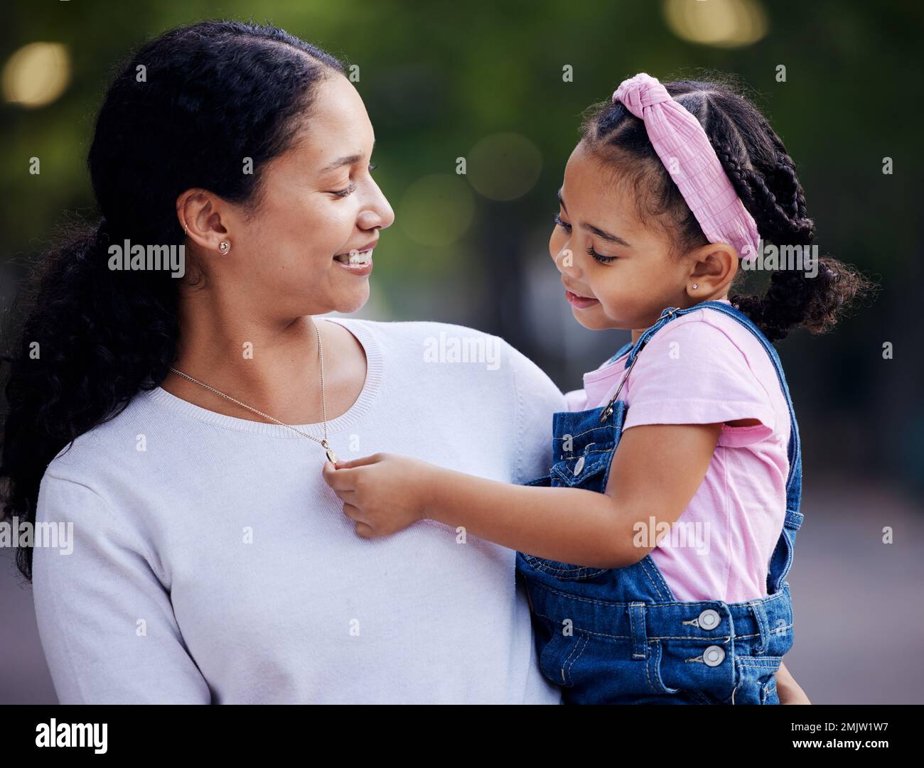 Family, mother and carrying little girl with smile for outdoor bonding and hugging at a park ...
