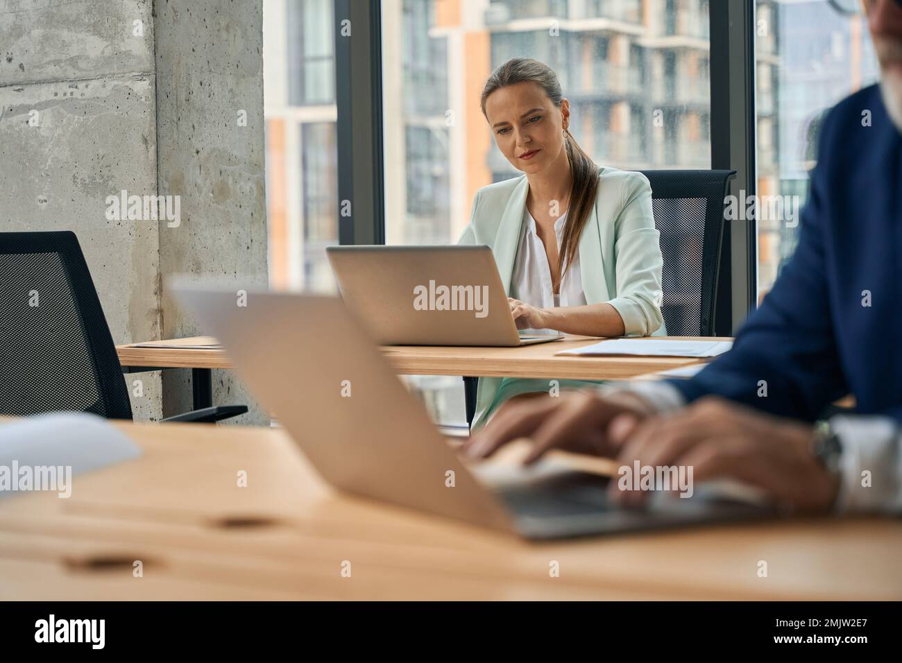 Concentrated office workers busy completing tasks on their laptops ...