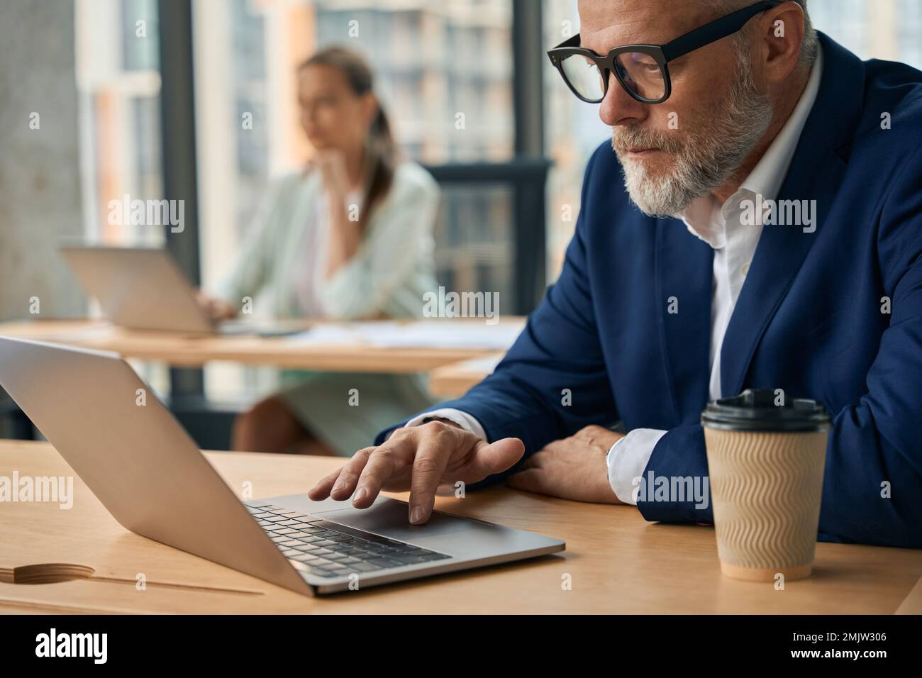 Aging businessman looking at laptop screen seriously while ...