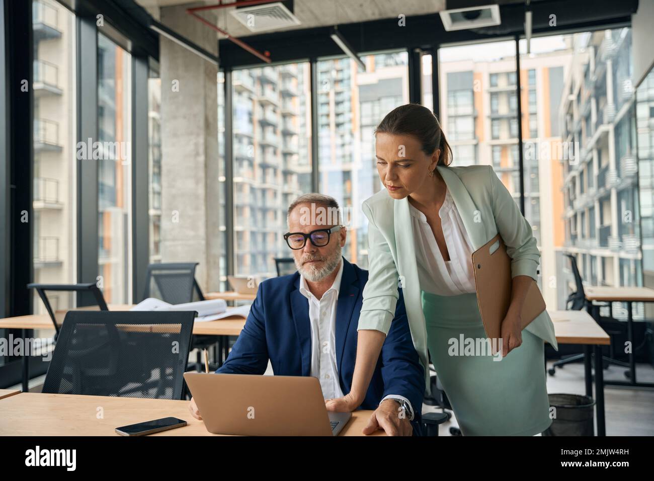 Focused office colleagues working on laptop with serious faces Stock ...