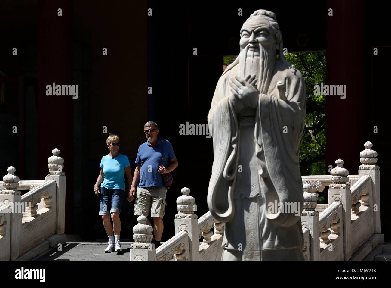 Foreign tourists walk past a statue of ancient Chinese philosopher ...