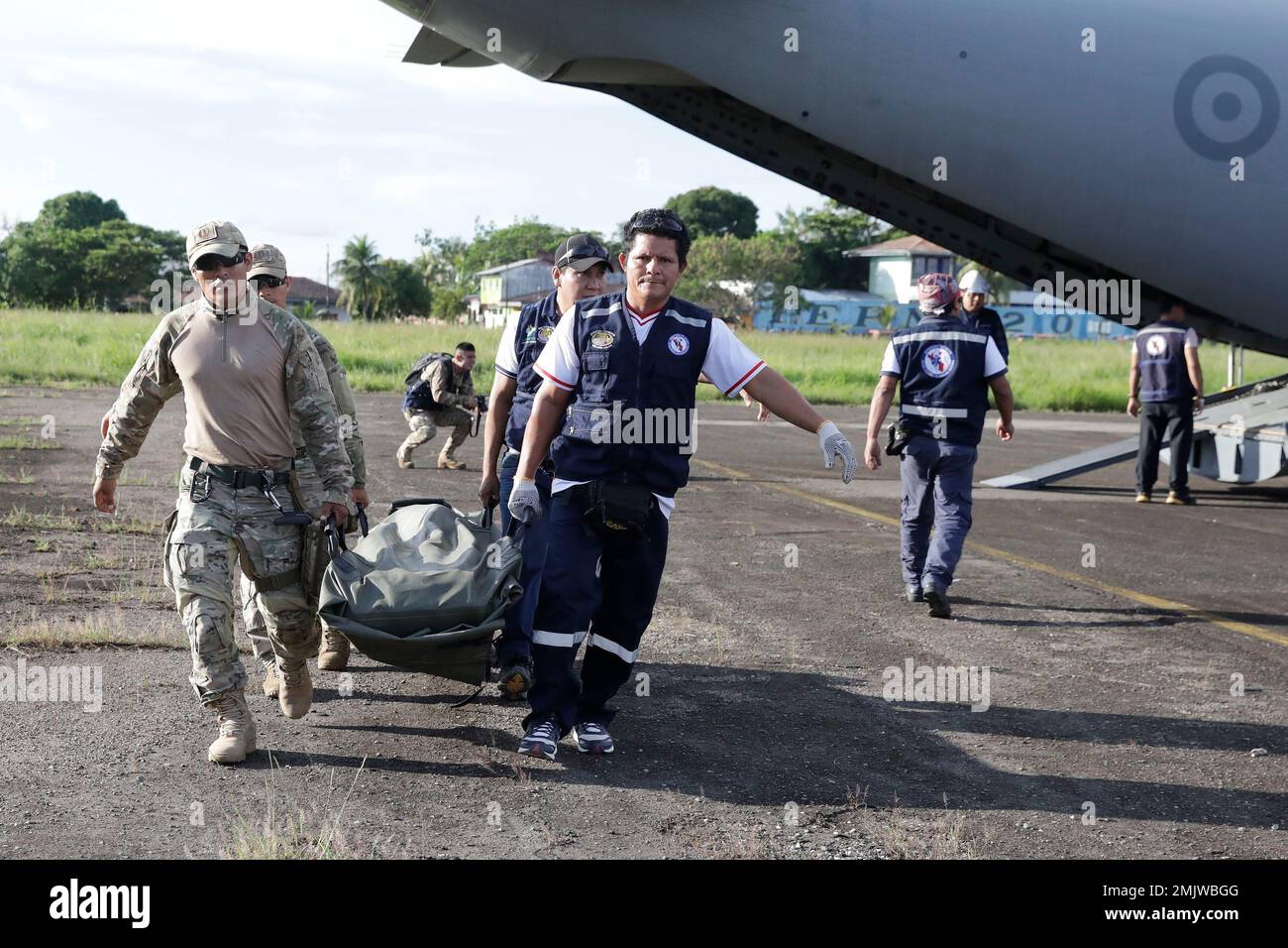 Soldiers and health brigade members carry equipment from a plane to be ...