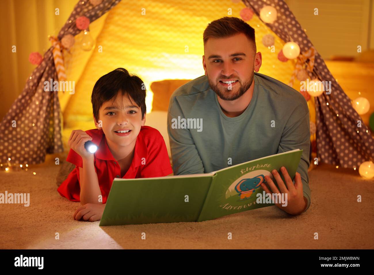 Father and son with flashlight reading book at home Stock Photo - Alamy
