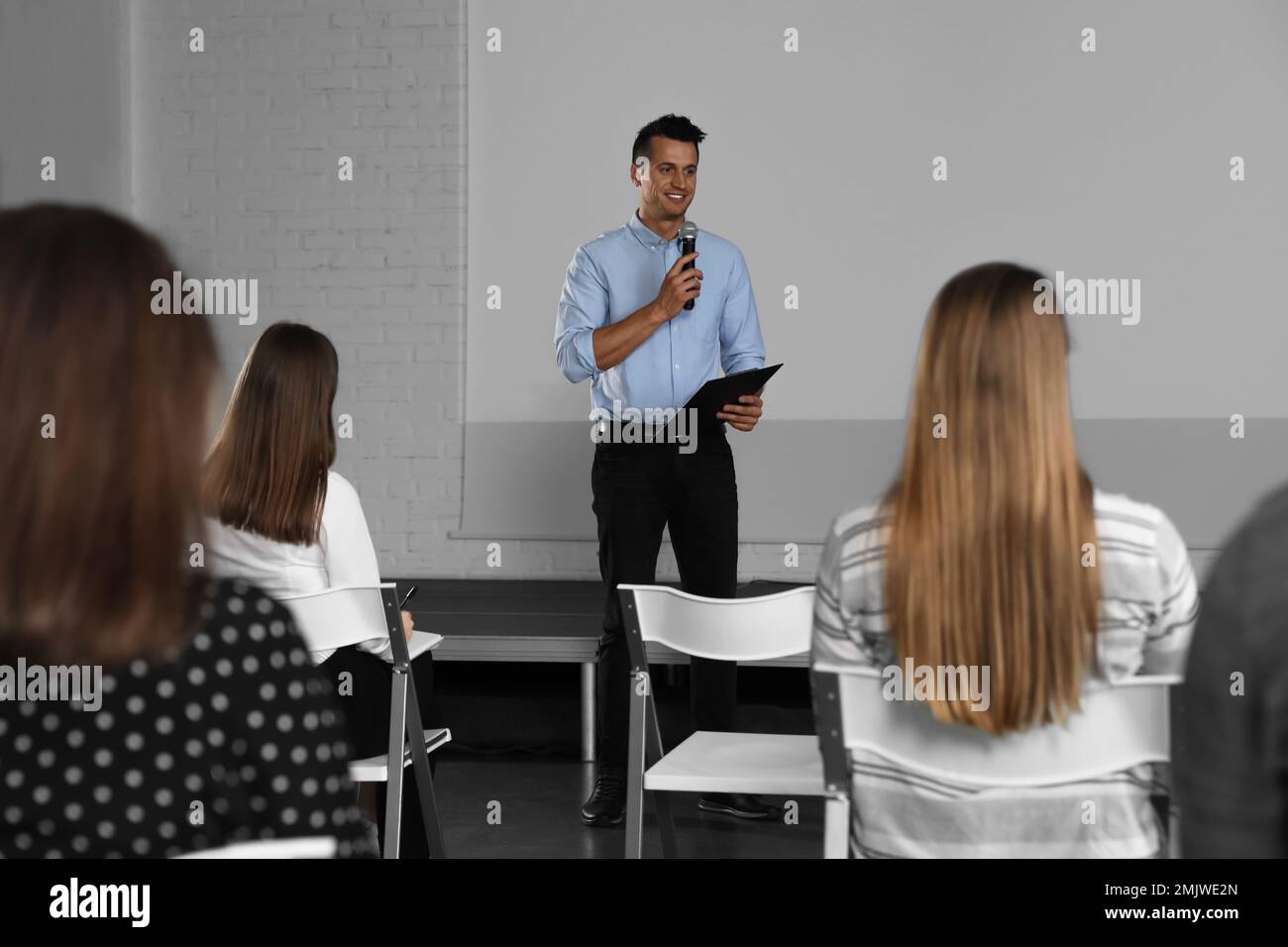 Male business trainer giving lecture in conference room with projection ...