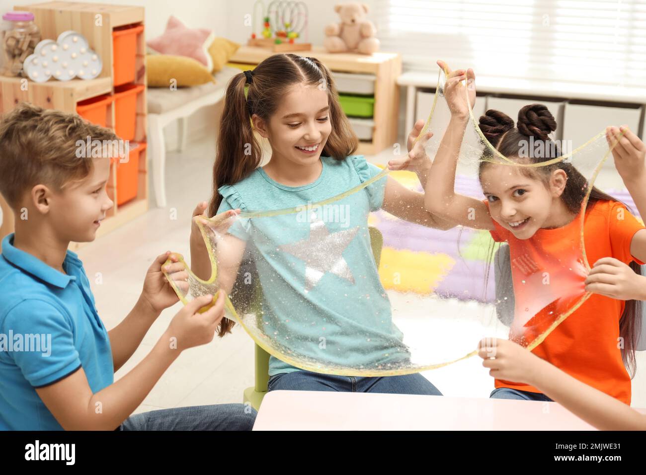 Happy children playing with slime at table indoors Stock Photo - Alamy