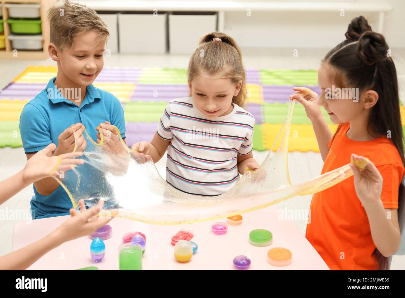 Happy children playing with slime at table indoors Stock Photo - Alamy