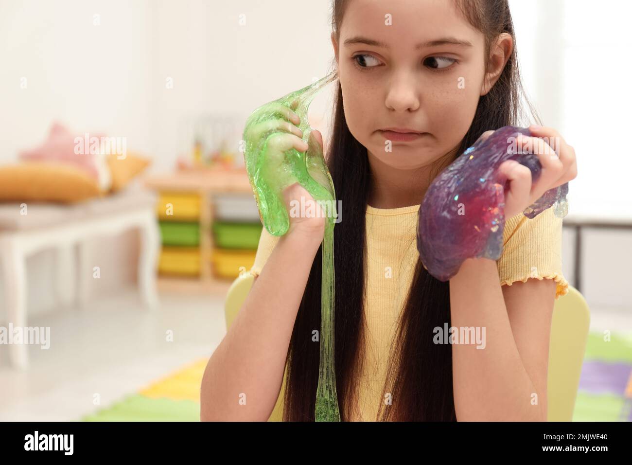 Emotional little girl playing with slime in room Stock Photo - Alamy