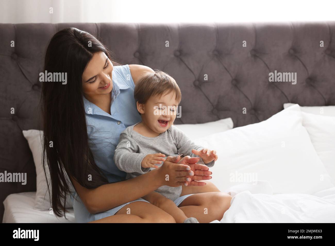 Young nanny with cute little baby in bedroom Stock Photo - Alamy