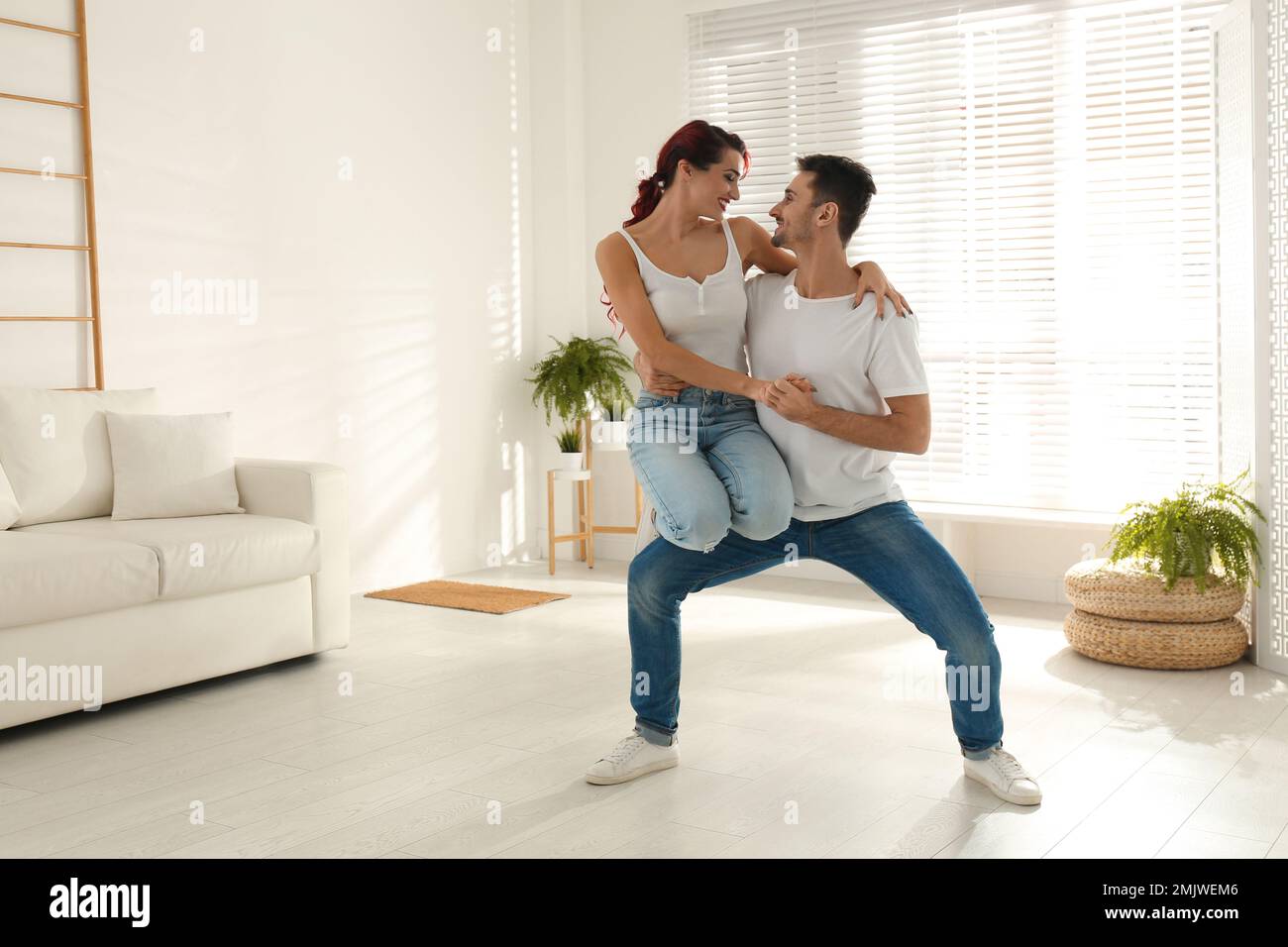 Beautiful young couple dancing in living room Stock Photo - Alamy