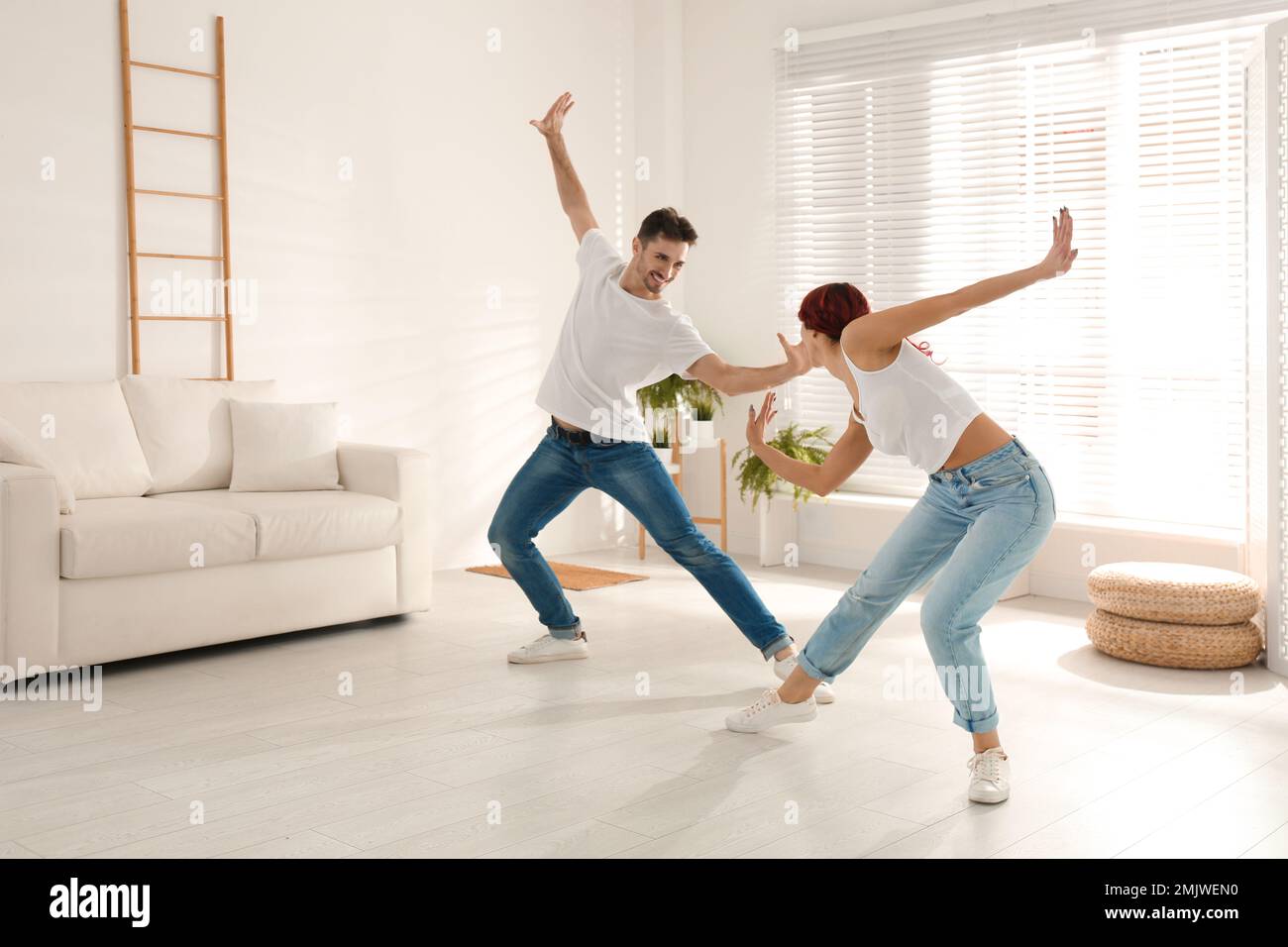 Beautiful young couple dancing in living room Stock Photo - Alamy
