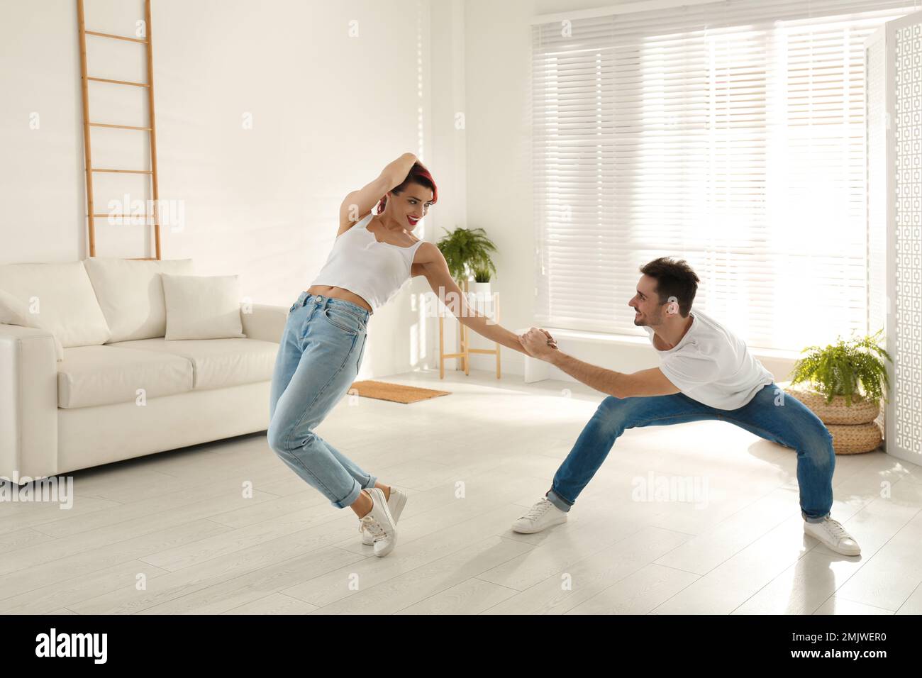 Beautiful young couple dancing in living room Stock Photo - Alamy