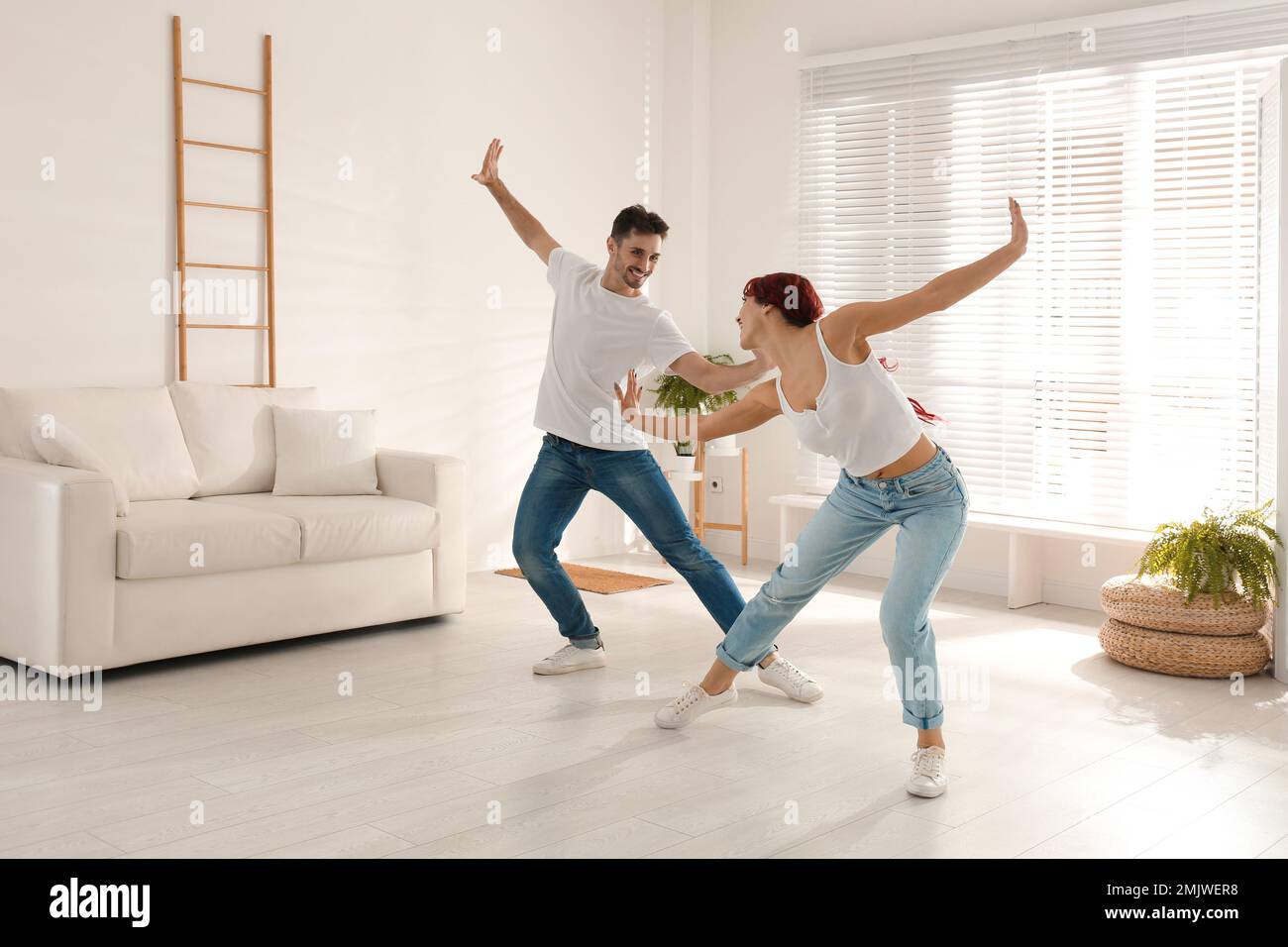 Beautiful young couple dancing in living room Stock Photo - Alamy