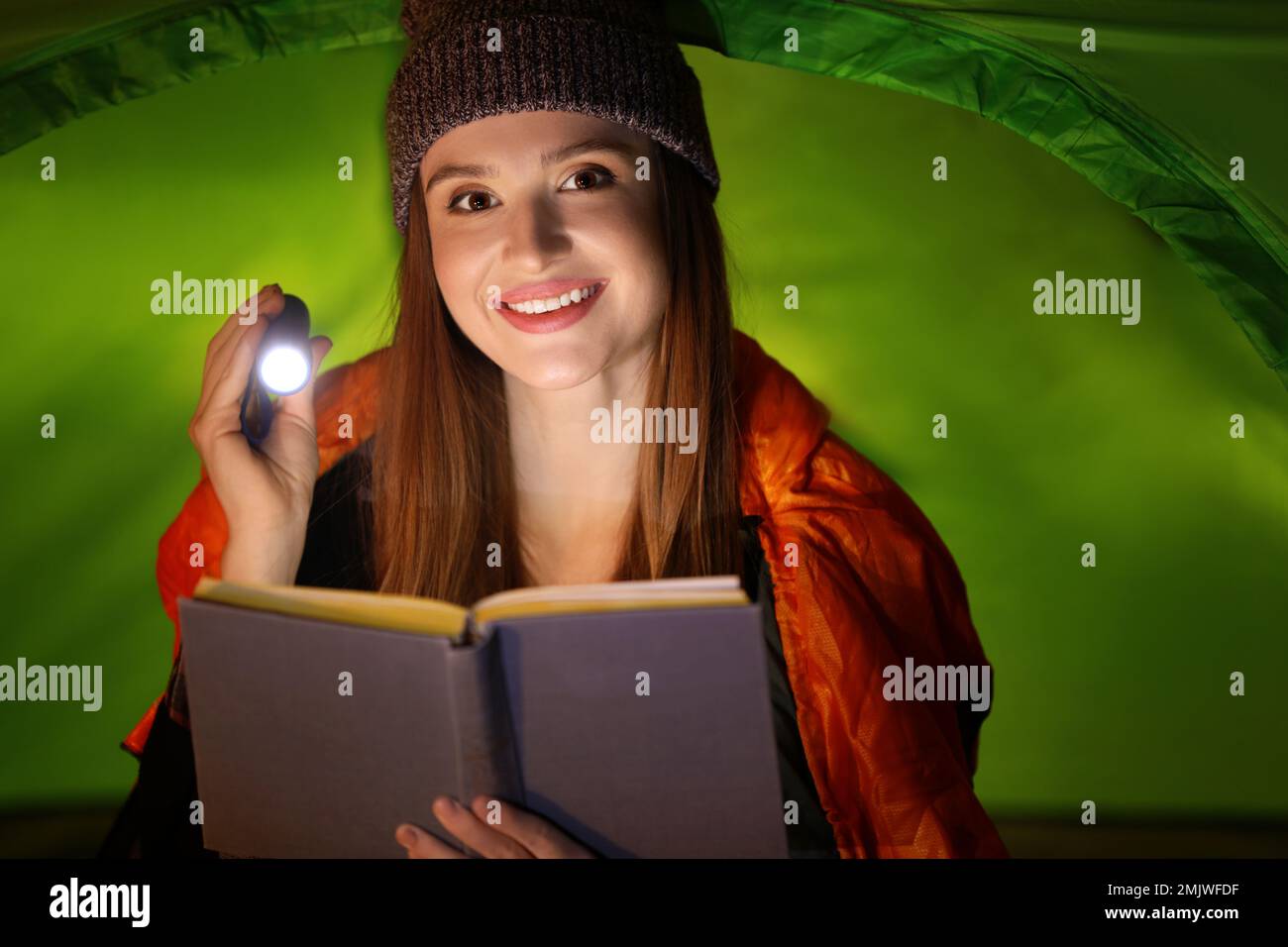 Young woman with flashlight reading book in tent Stock Photo - Alamy