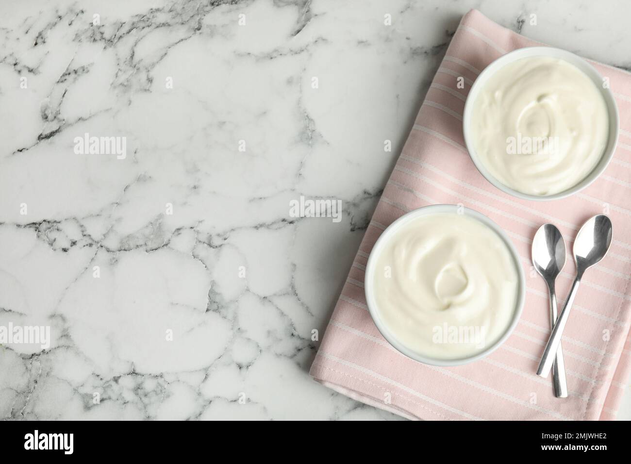 Tasty organic yogurt on white marble table, top view. Space for text ...