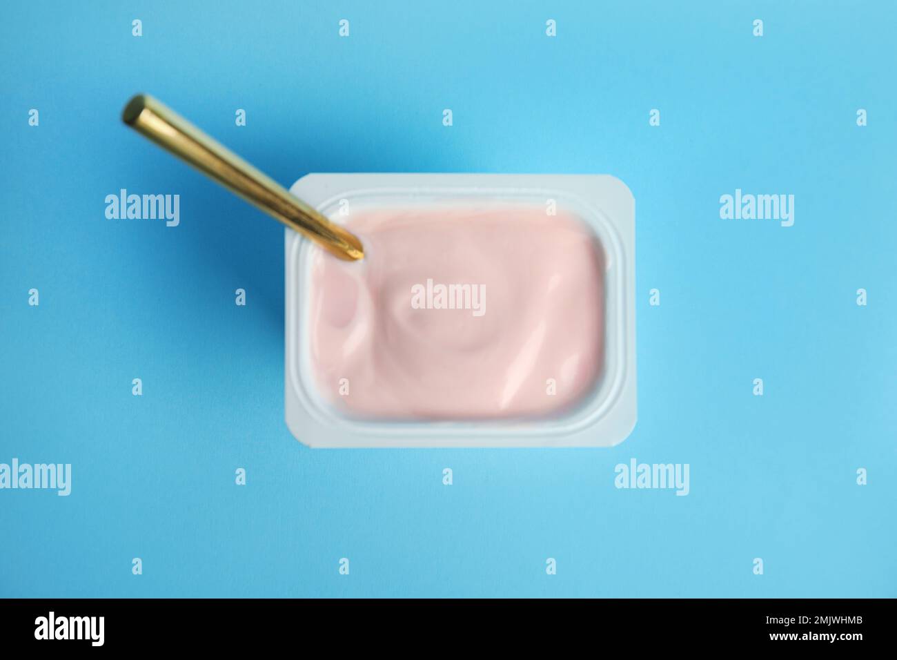 Tasty organic yogurt with spoon on light blue background, top view ...