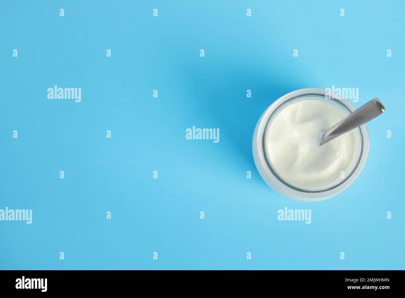 Tasty organic yogurt on light blue background, top view. Space for text ...