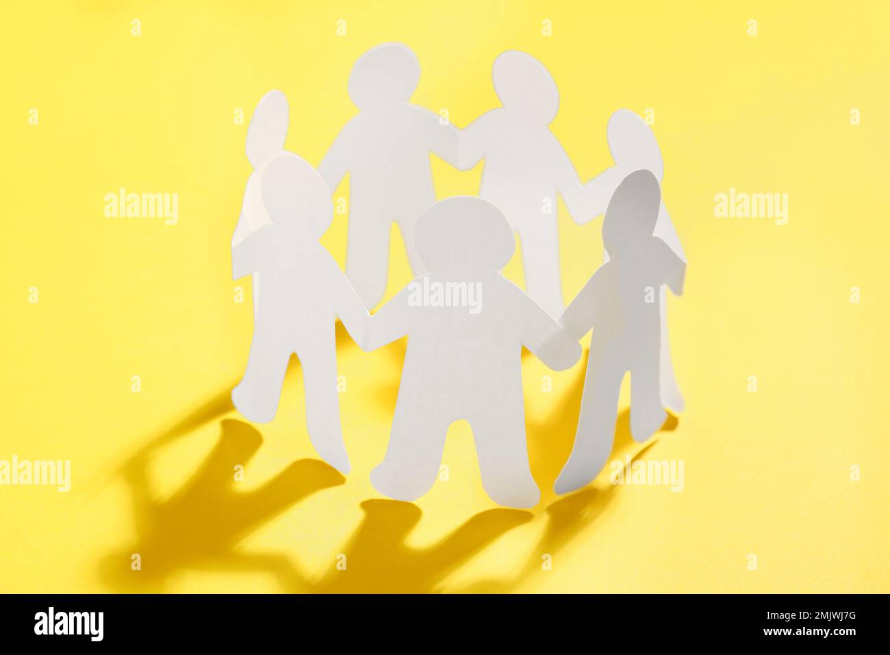 Paper people chain making circle on yellow background. Unity concept ...