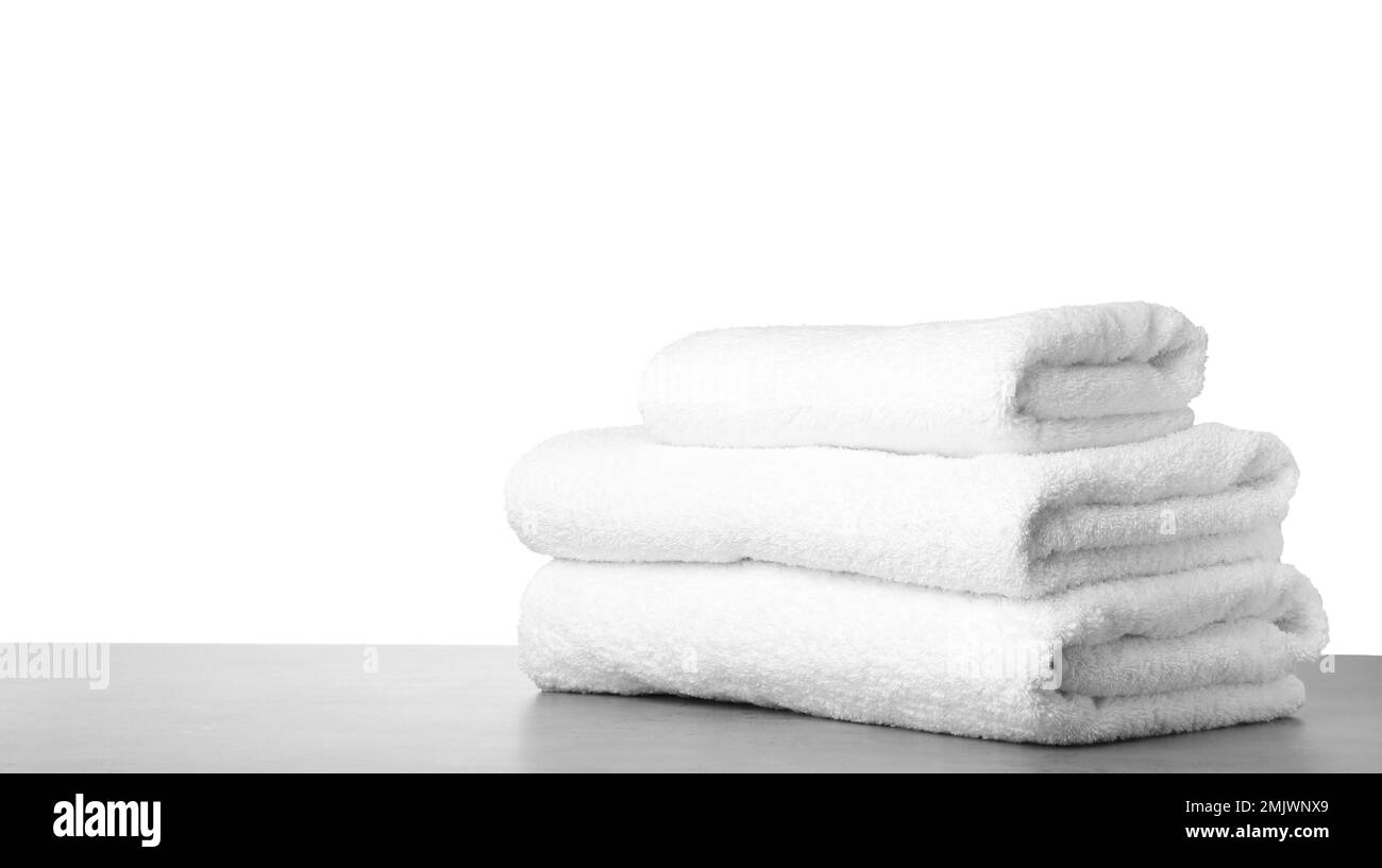 Folded fresh clean towels for bathroom on table against white ...