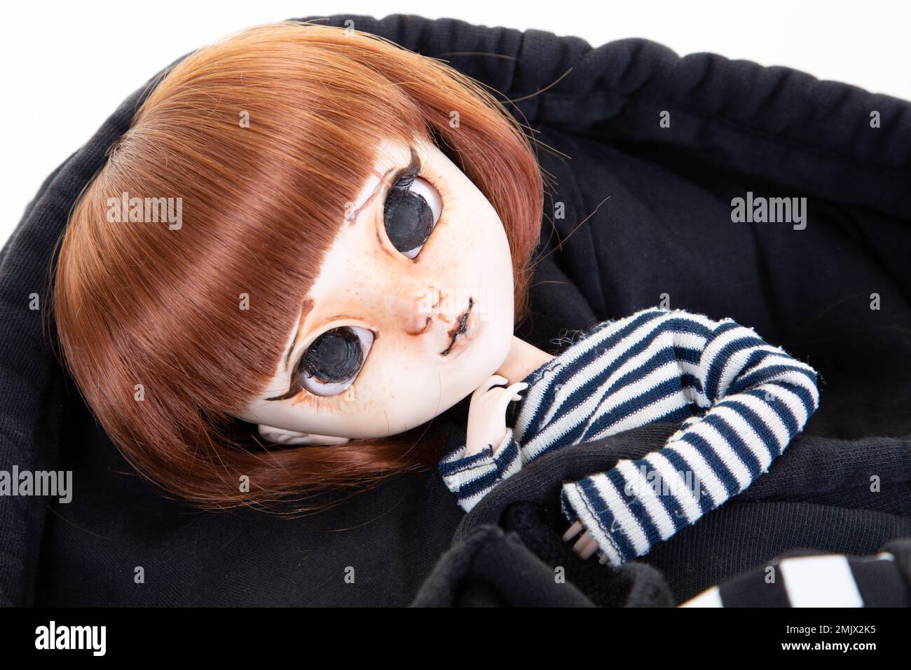 Red-haired doll lying in black cap of child girl Stock Photo - Alamy