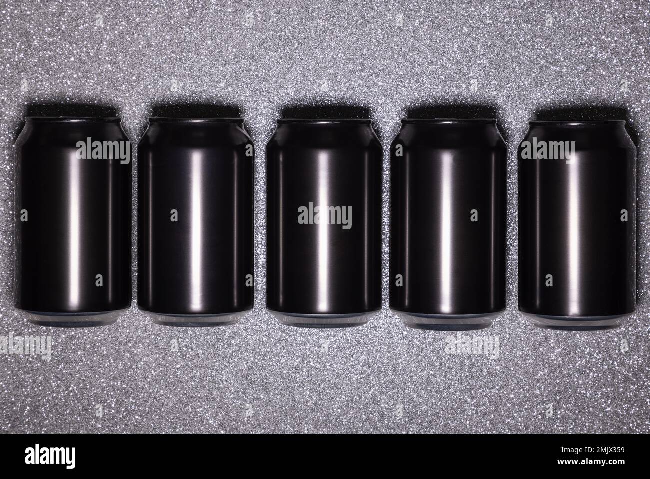Photo of five black blank aluminium cans in a row with hard lighting on ...