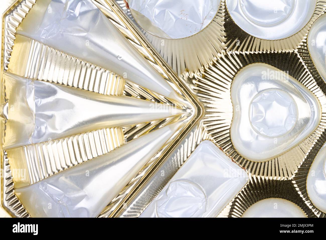 Close up shot of empty box of chocolates. Shiny gold plastic texture of ...