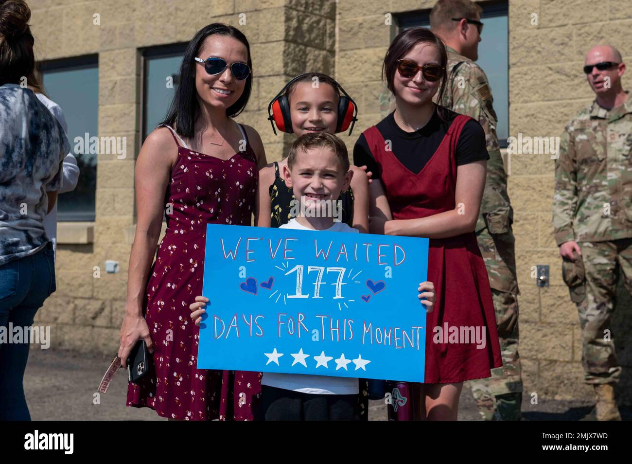 Family poses with a sign for a photograph at Fairchild Air Force Base ...