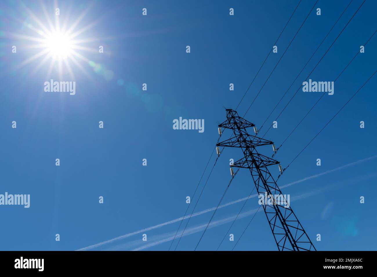 high power electrical lines electricity pylon in blue sky with sun ...