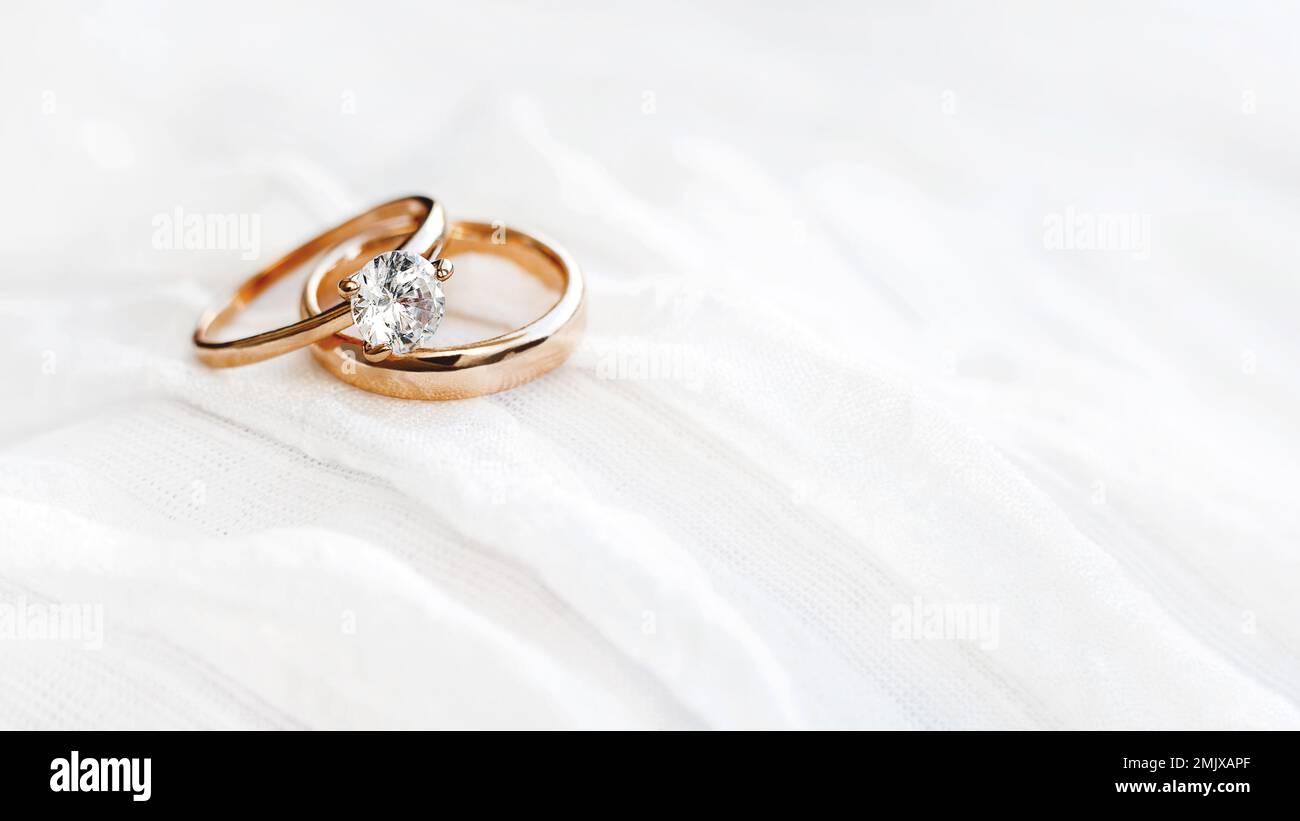 Pair of golden wedding rings on white textile background with copy ...