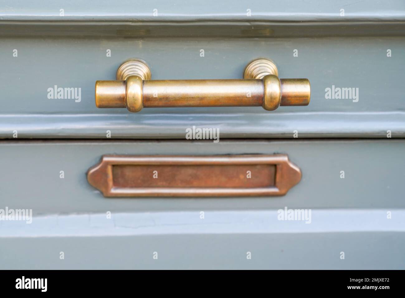 Shiny copper mailbox door handle metal postbox on green blue old ...
