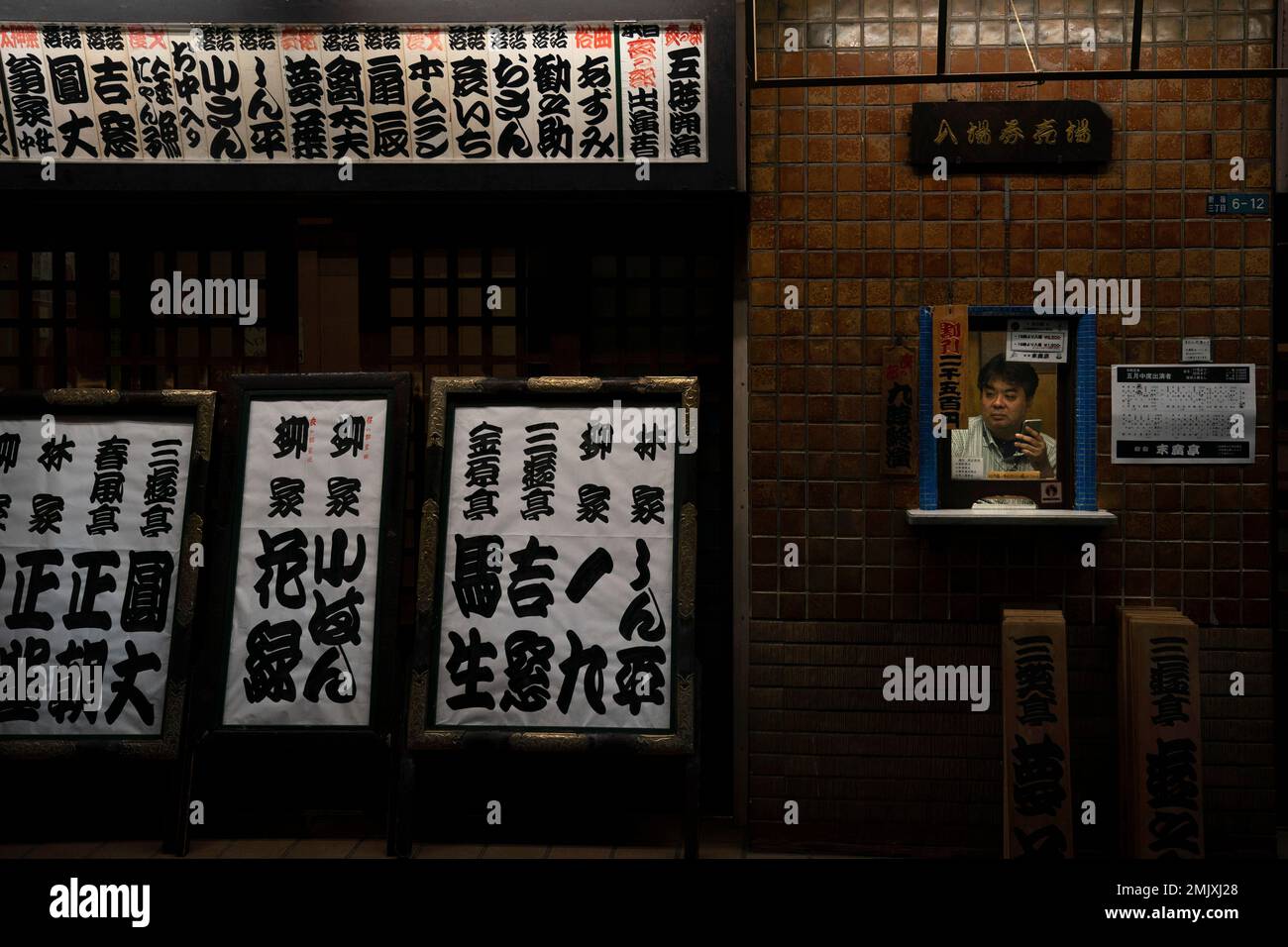 An employee sits in a ticket booth at Suehirotei yose, an entertainment ...